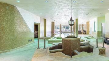 Uma área de spa com uma banheira de hidromassagem central, áreas de estar e vista para o exterior.