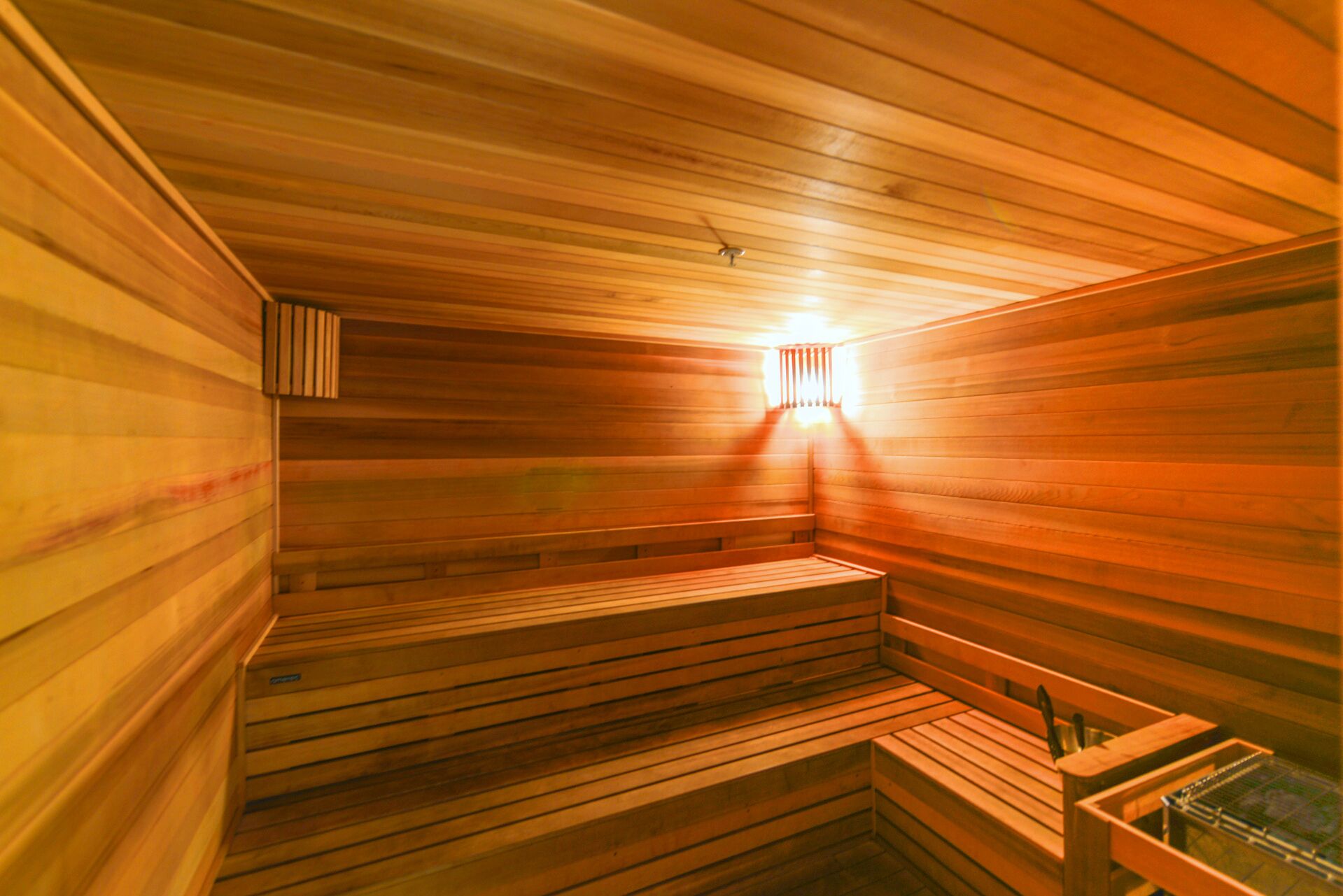 Uma sauna com bancos de madeira e uma luminária.