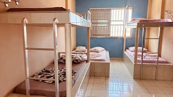 Um dormitório com beliches, uma janela com persianas e um ventilador de teto.