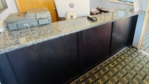 Uma mesa de recepção com um computador, uma impressora e um telefone.