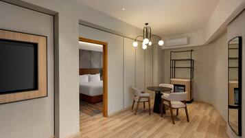 Quarto de hotel com cama, secretária com cadeiras, luminária pendente e um espelho grande.