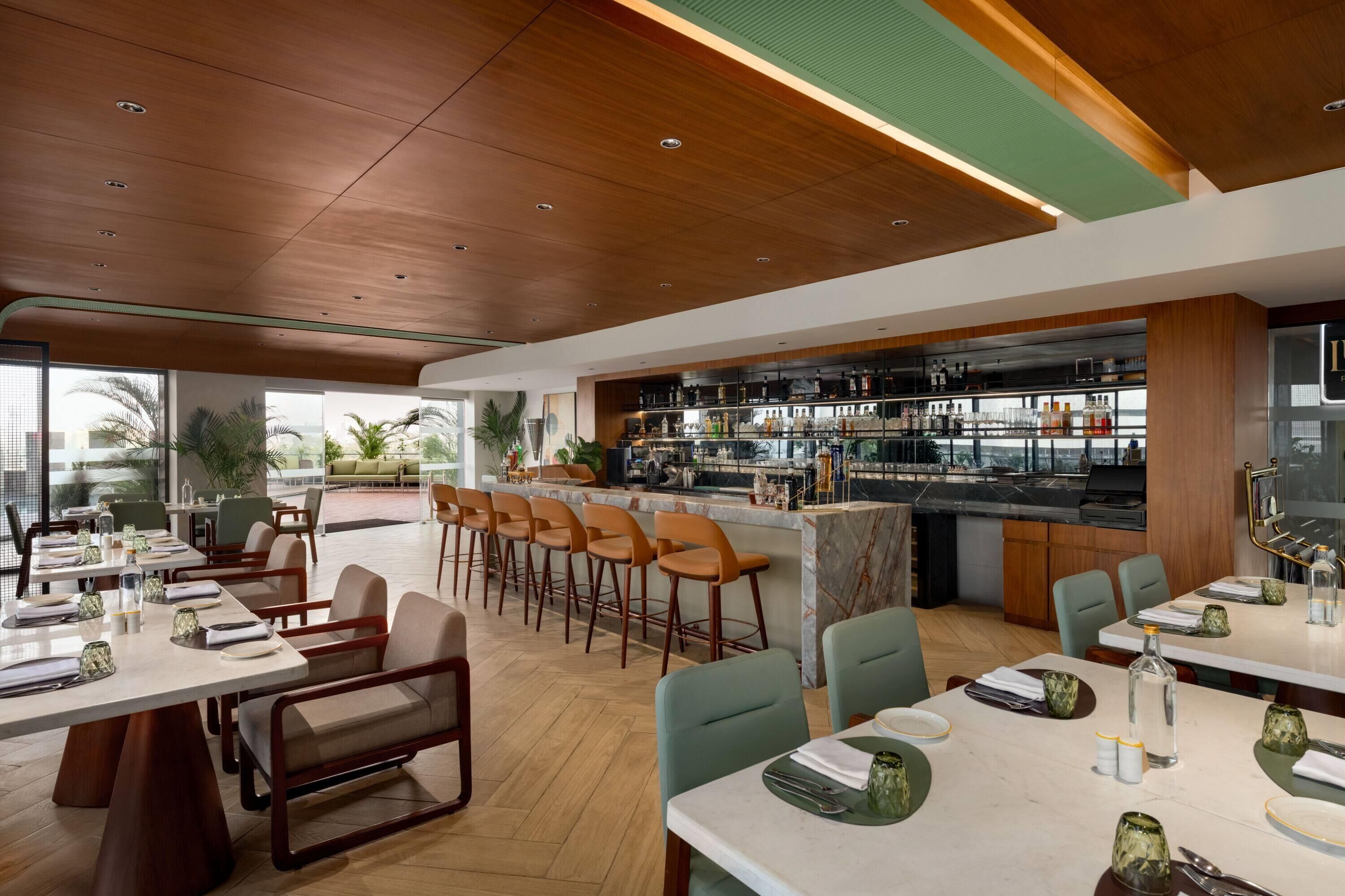 Restaurante moderno com teto de madeira, área de bar e disposição dos assentos.