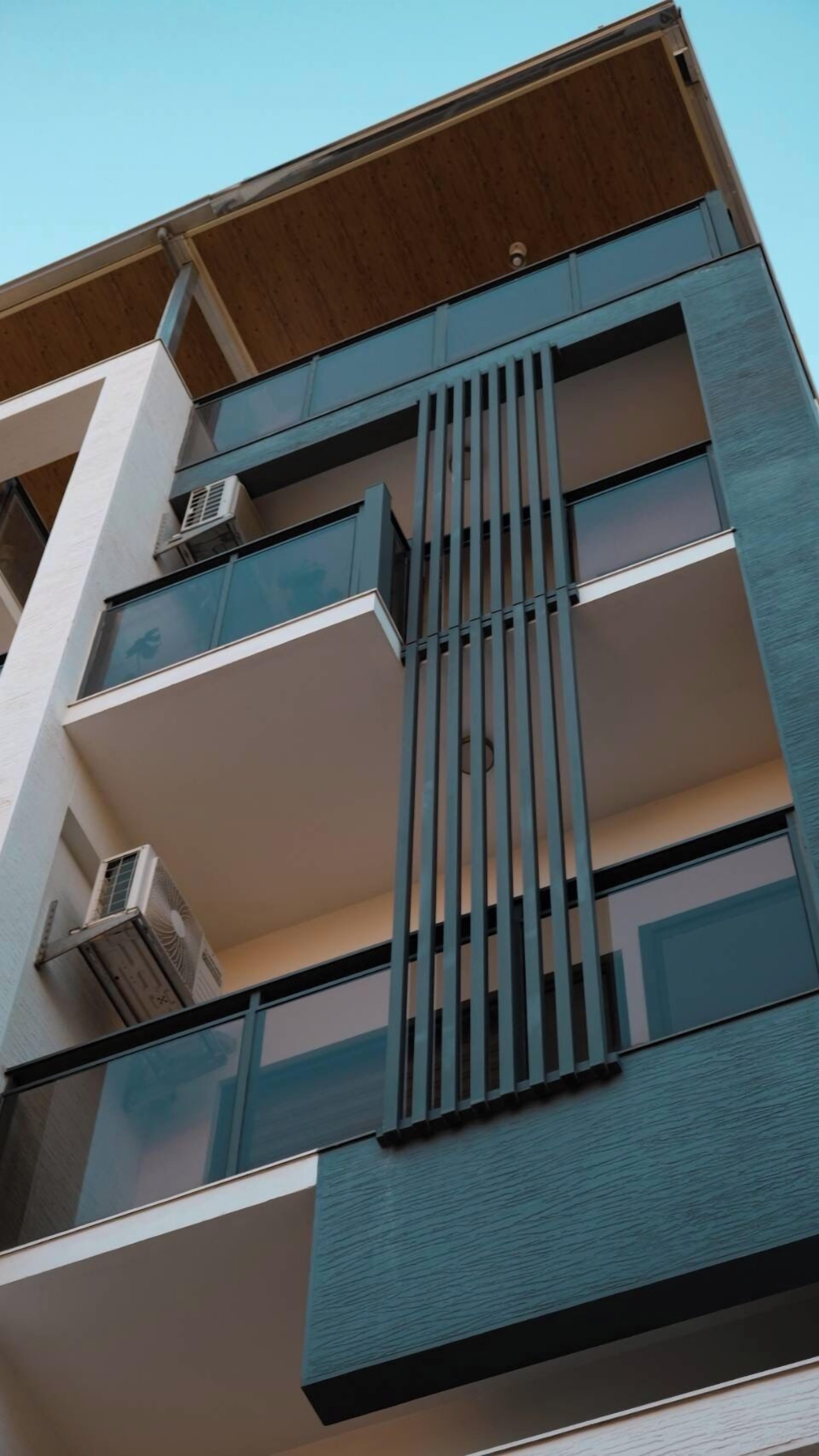 Um edifício de vários andares com varandas, aparelhos de ar condicionado e design arquitetônico moderno.