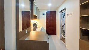 Corredor com cozinha, geladeira e porta com detalhe decorativo.
