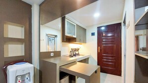 Quarto de hotel compacto com cozinha compacta, banheiro pequeno e porta de madeira.