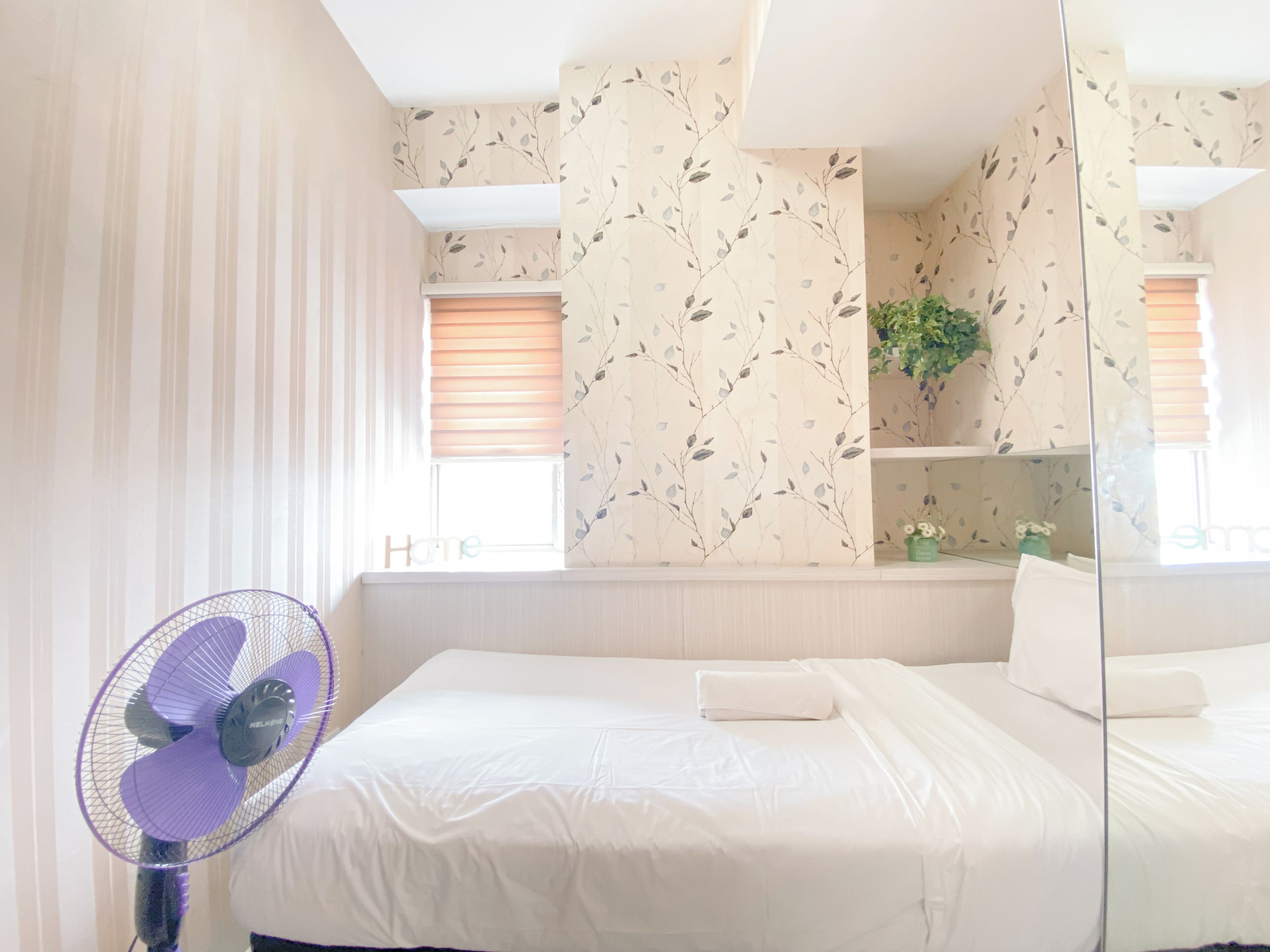 Quarto com cama, ventilador e janela com persianas.