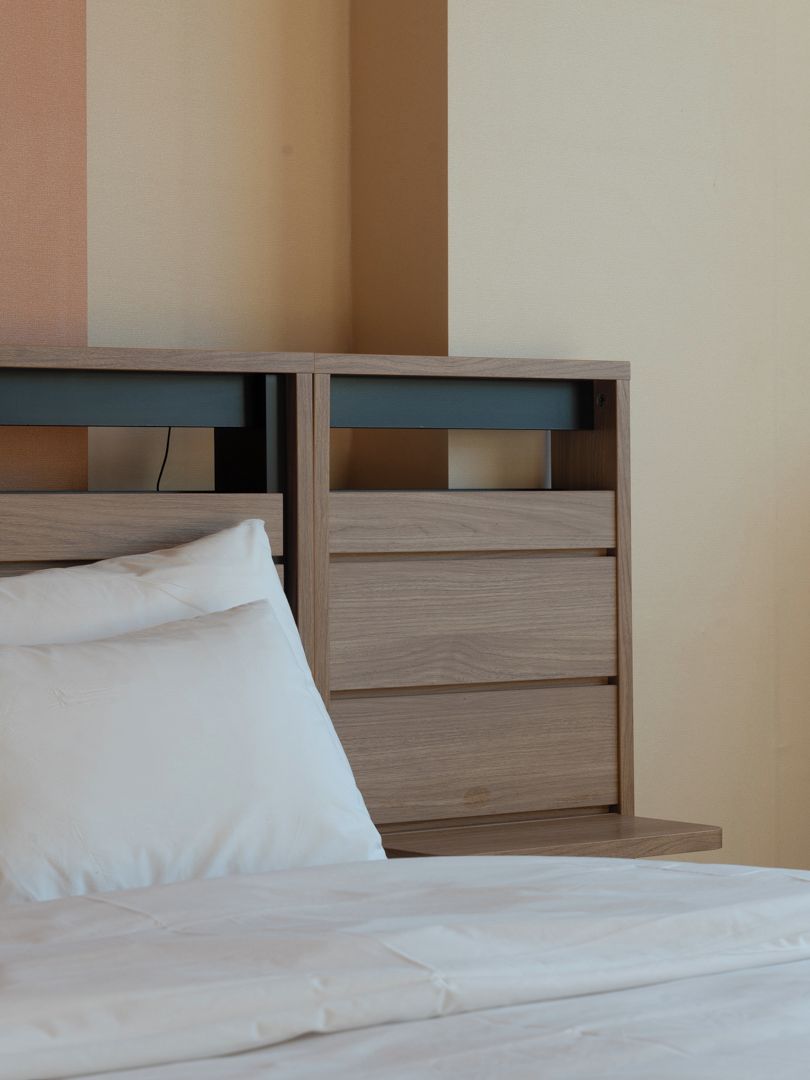 Uma cama com cabeceira de madeira e colchão branco.