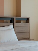 Uma cama com cabeceira de madeira e colchão branco.