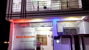 Um prédio de dois andares com uma placa na entrada que diz "Hotel Siyaram".