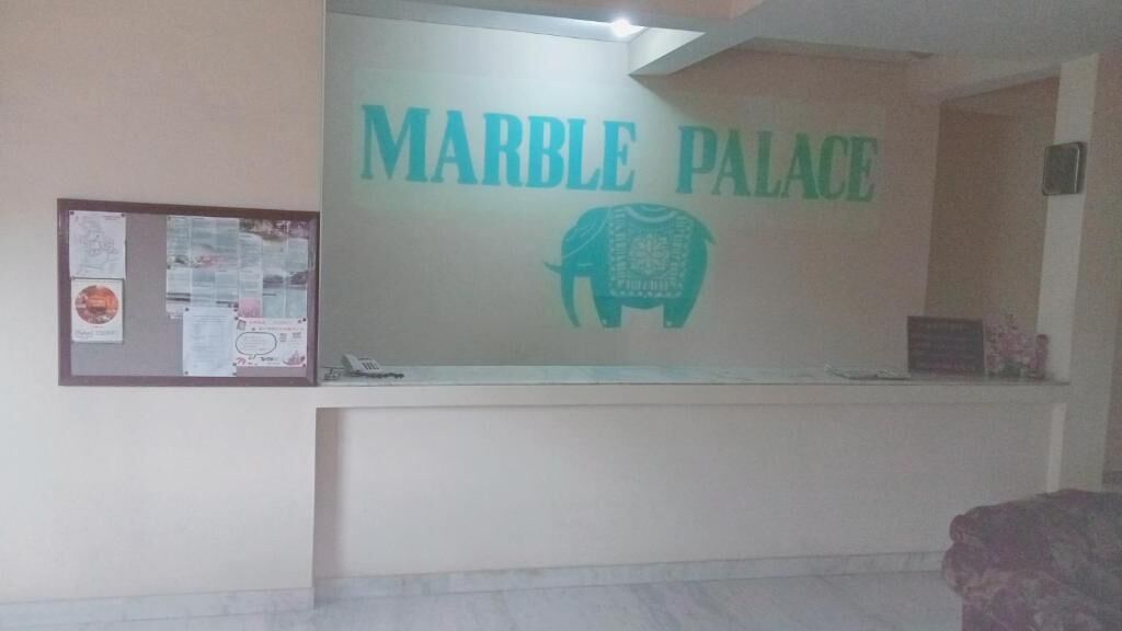 Uma mesa de recepção com uma placa que diz 'MARBLE PALACE' e um desenho de elefante.