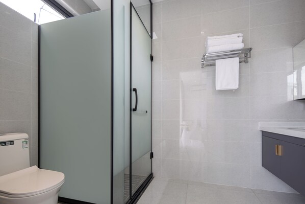Um banheiro moderno com box de vidro, vaso sanitário e toucador com porta-toalhas.