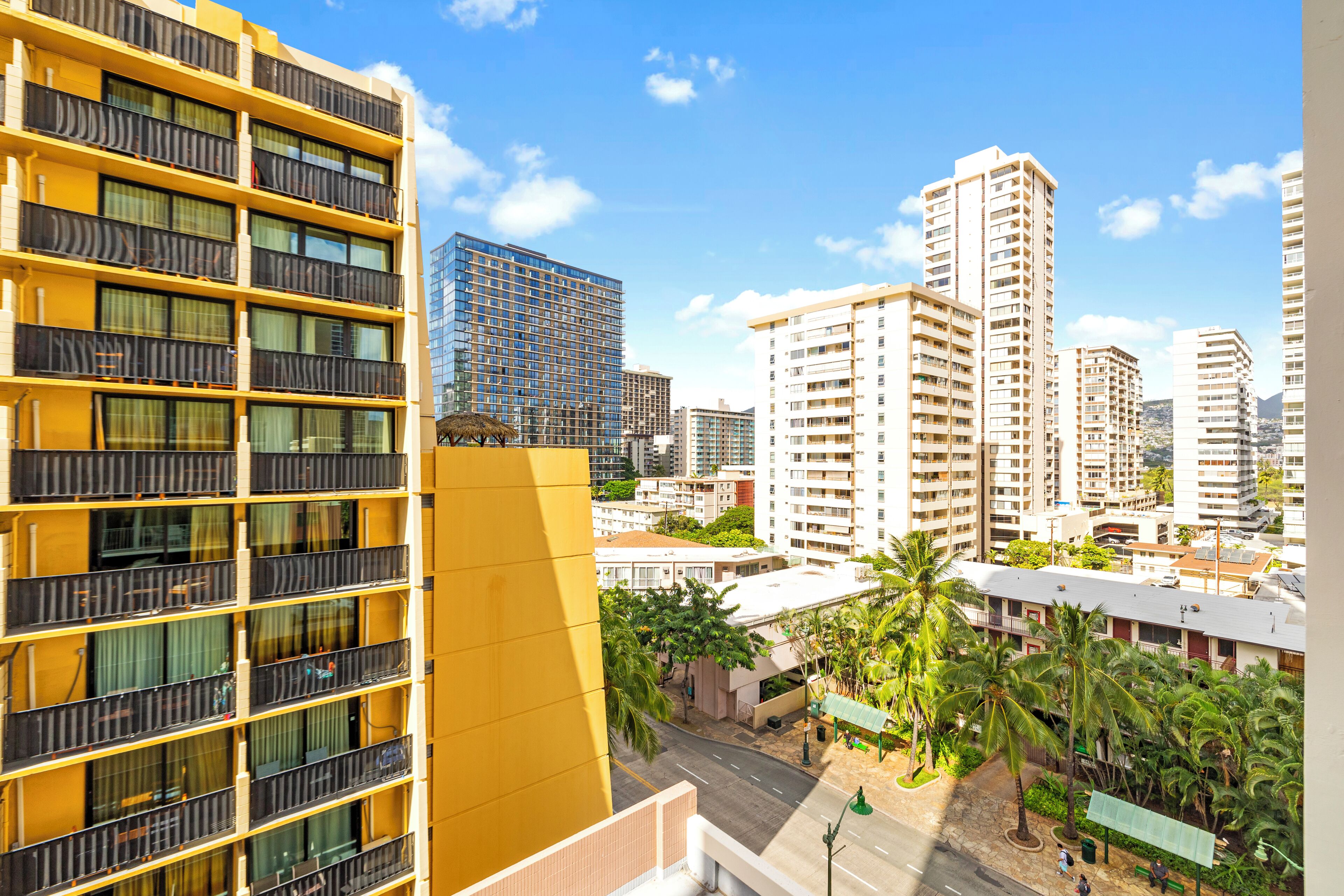 Um edifício alto com várias varandas, um prédio de vidro moderno e edifícios residenciais ao redor.