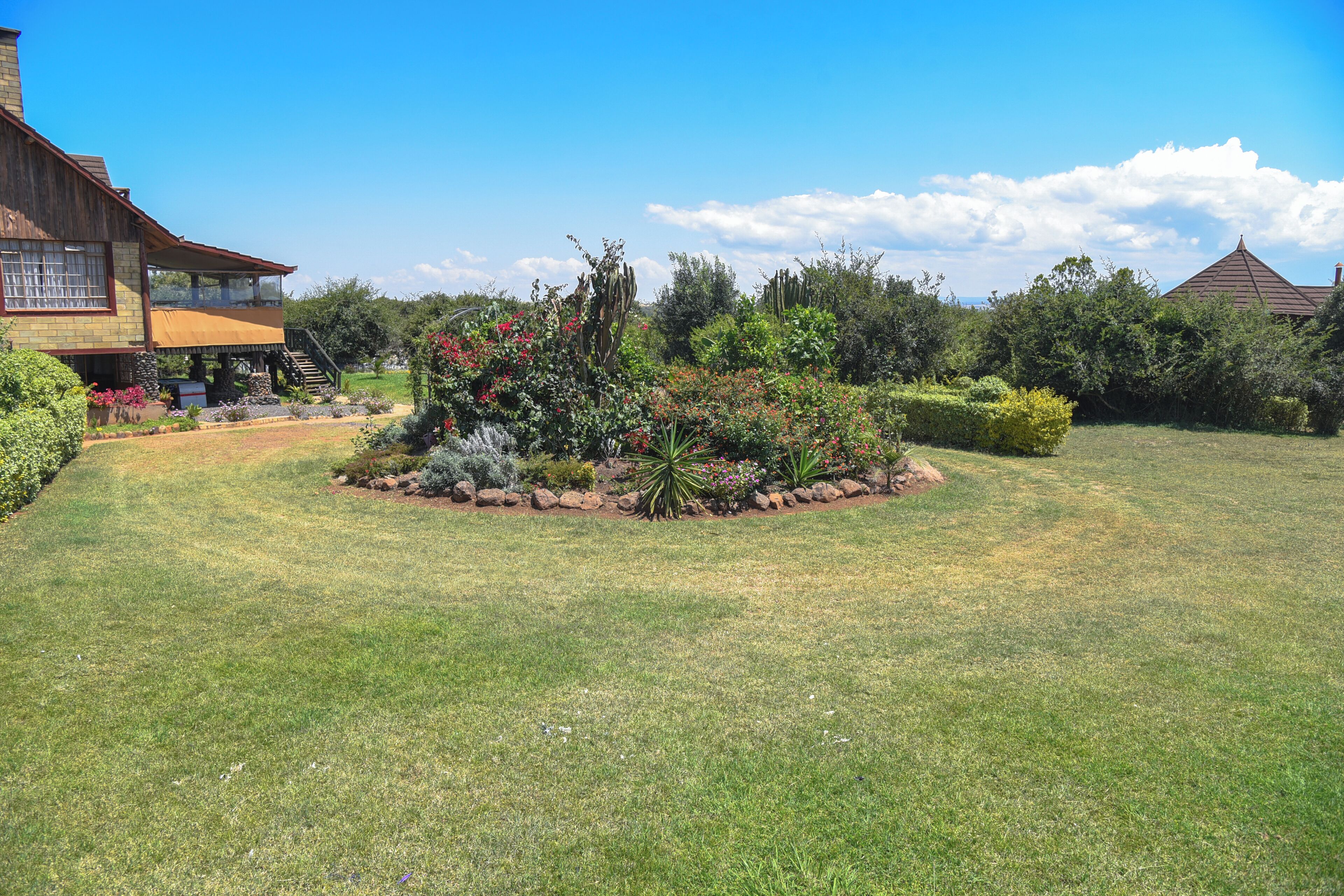 Uma casa com um jardim amplo, uma escadaria visível e um céu claro.