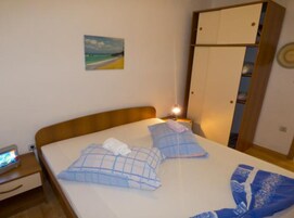 Quarto com cama, mesa de cabeceira, luminária, guarda-roupa e um quadro na parede.