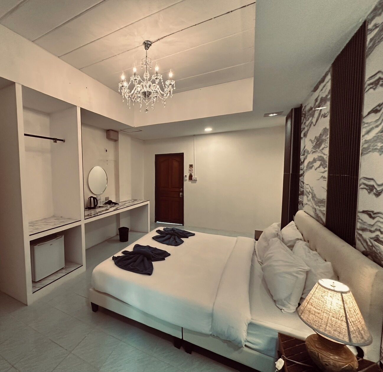 Quarto moderno com cama, luminária de cabeceira e um lustre.