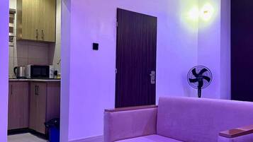 Sala de estar moderna com um sofá, uma mesinha e uma área de cozinha visível ao fundo.