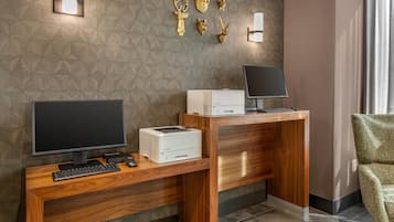 Uma mesa de escritório moderna com um computador, impressora e teclado.