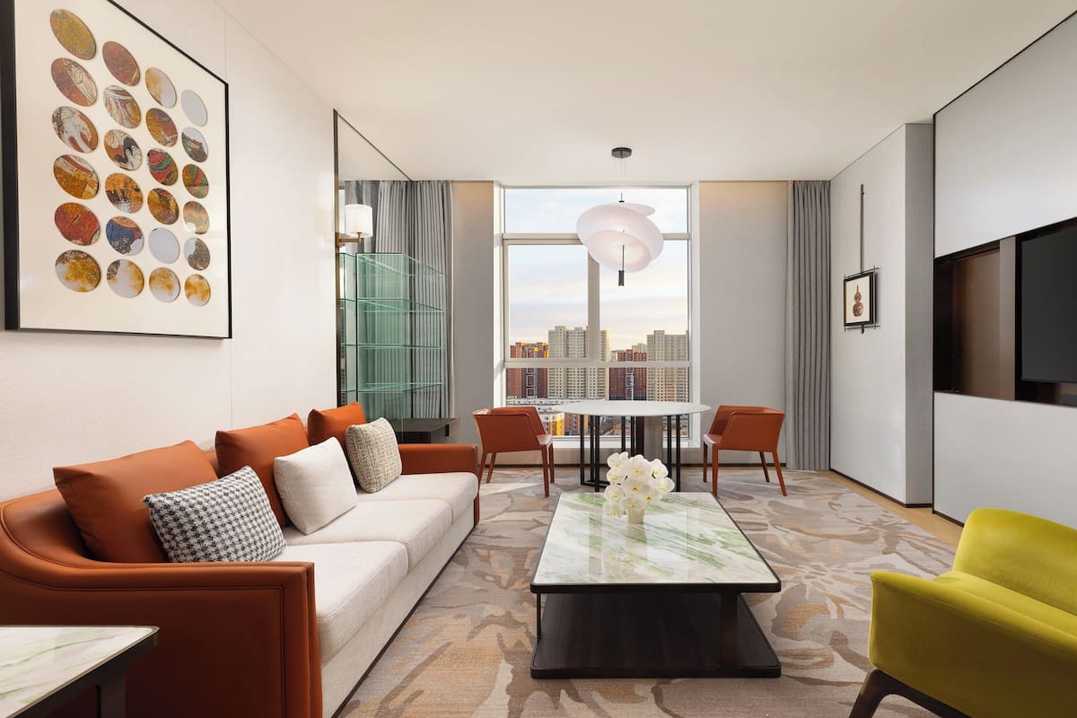 Uma sala de estar moderna com um sofá, cadeiras, uma mesa de centro e uma televisão.