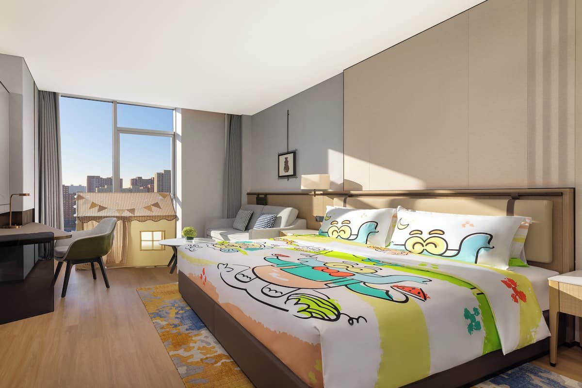 Quarto de hotel moderno com uma cama grande, uma escrivaninha e vista para o horizonte da cidade.