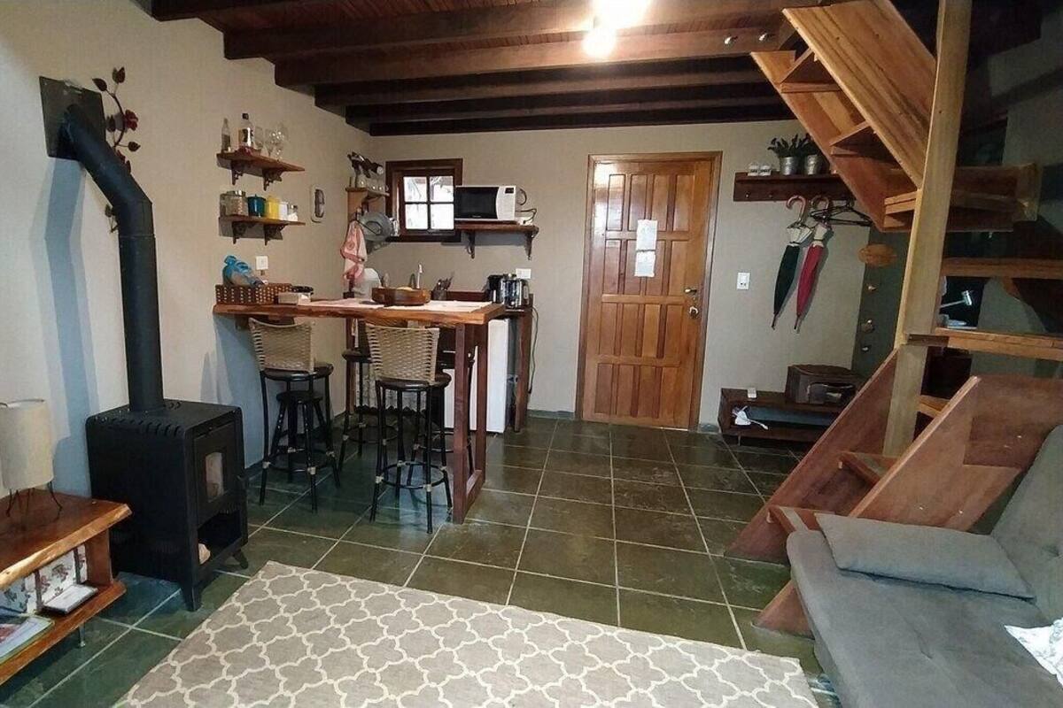 Uma sala de estar aconchegante com lareira, móveis de madeira e TV fixada na parede.