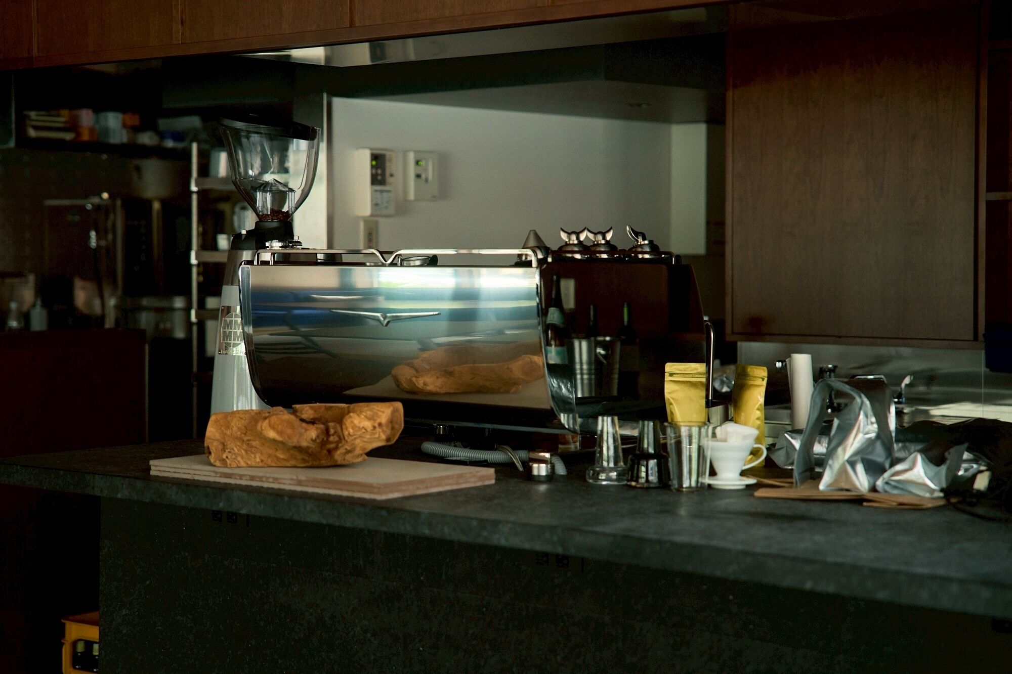 Uma bancada de cozinha com uma cafeteira, um pão e diversos utensílios.