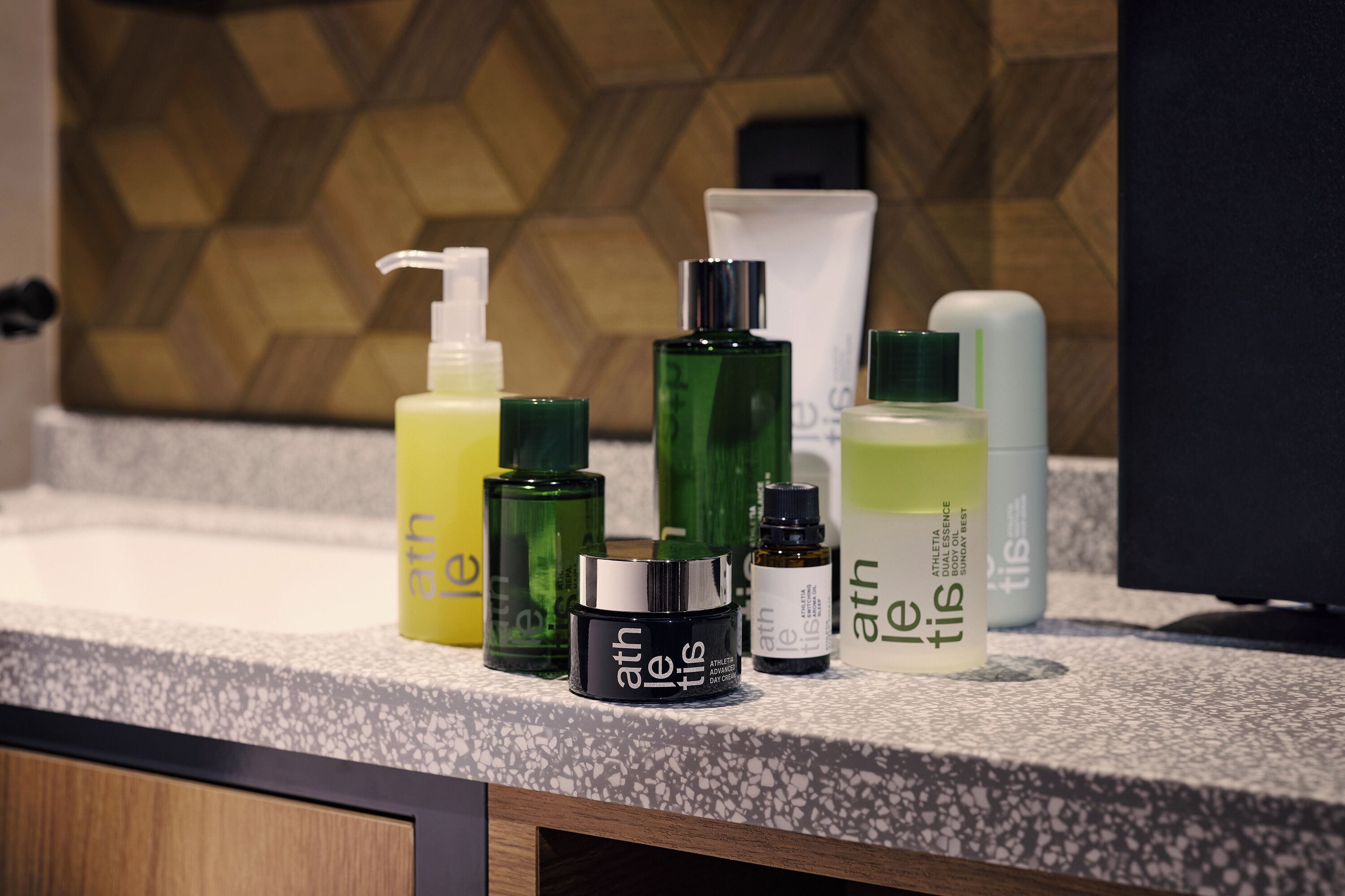 Uma bancada de banheiro com diversos produtos de higiene pessoal, incluindo frascos e um dosador.