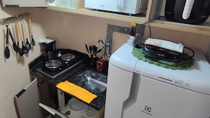 Uma cozinha compacta com micro-ondas, mini-geladeira, fogão e pia.
