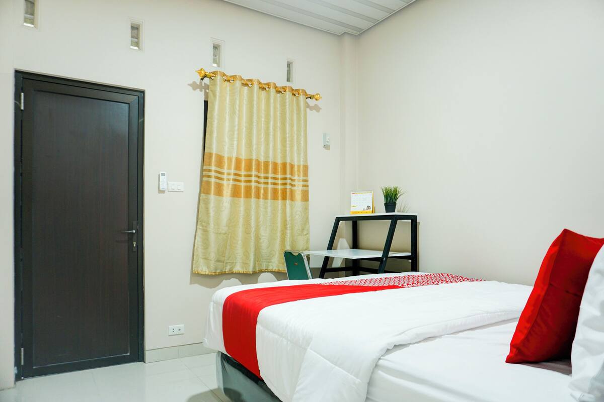 Quarto de hotel com uma cama, uma mesa e uma porta.