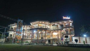 Um hotel com vários andares, um letreiro em destaque, varandas e fachada bem iluminada.