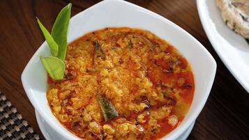 Uma tigela de sopa com enfeite, uma tigela de molho e um prato com comida sobre uma mesa de madeira.