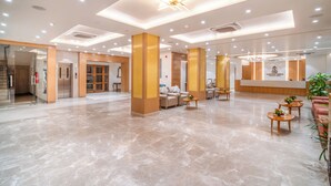 Um hall amplo com balcão de recepção, área de estar e design de teto moderno.