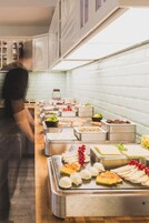 Uma mesa de buffet com diversos alimentos e uma pessoa ao fundo.