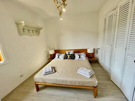 Quarto com cama, duas mesas de cabeceira, abajur, guarda-roupa e luminária de teto.