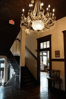 Uma escadaria imponente com um lustre, paredes de madeira e um quadro emoldurado.
