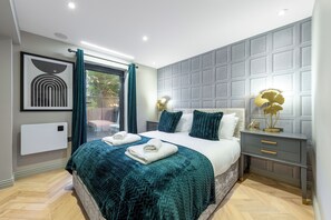 Quarto moderno com uma cama grande, mesa de cabeceira com abajur e vista pela janela.