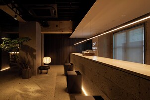 Uma área de recepção moderna com balcão de madeira, planta em vaso e um banco.