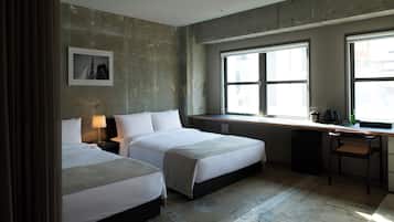Quarto de hotel com duas camas, uma escrivaninha, uma cadeira, uma janela e um quadro na parede.