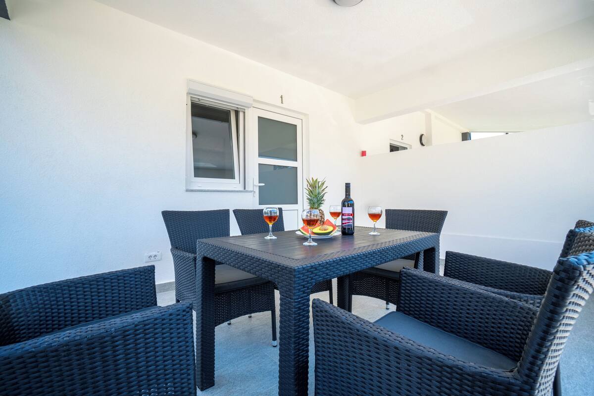 Uma área de refeições com uma mesa, cadeiras, uma janela e uma porta.