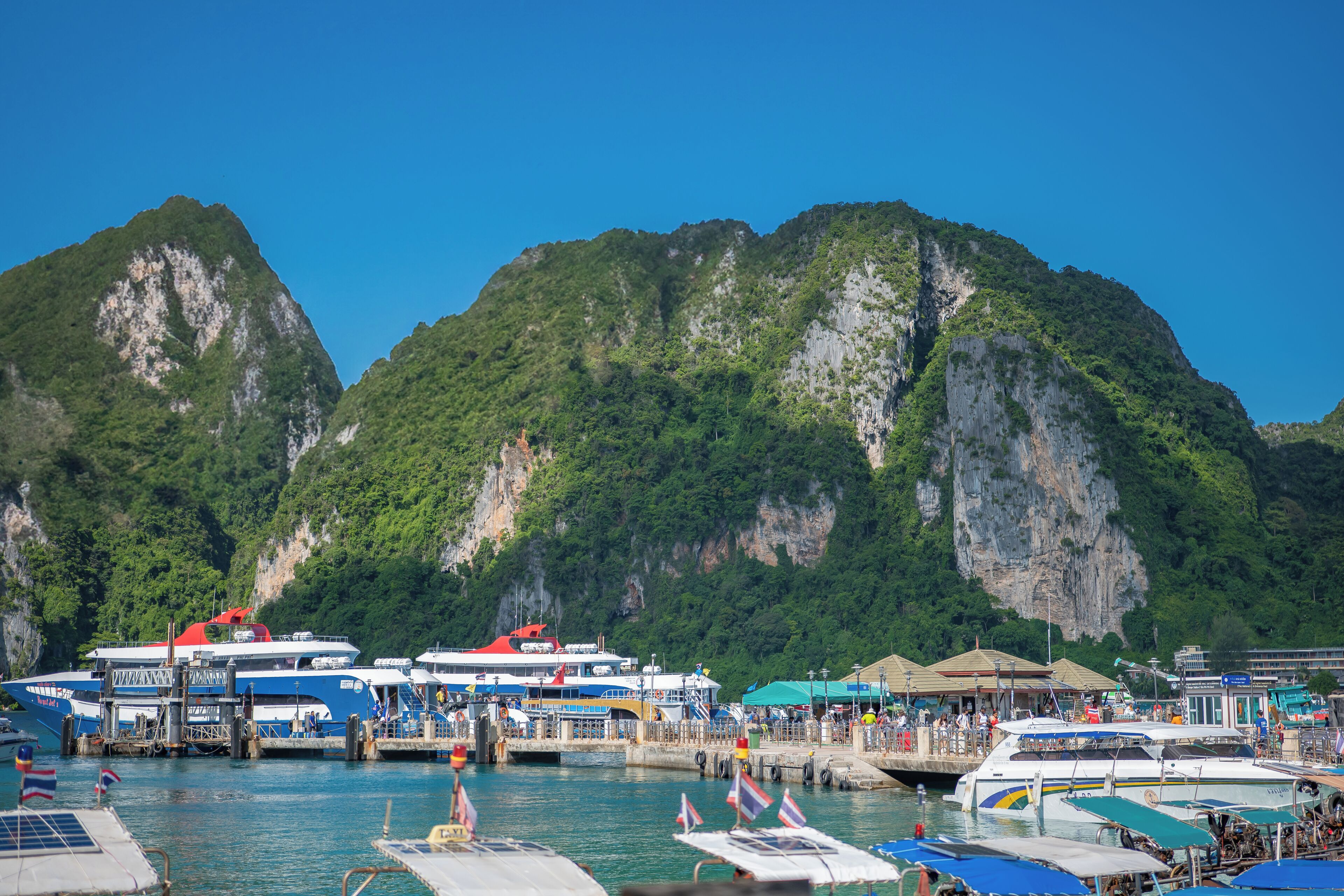 Marina com barcos atracados, um cais e montanhas ao fundo.