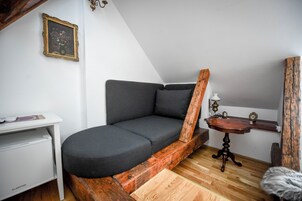Quarto estilo loft com sofá cinza embutido, uma pequena mesa de madeira e uma escrivaninha branca.