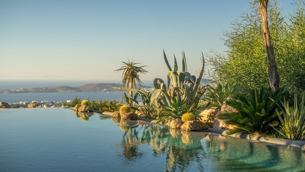 Piscina infinita com vista deslumbrante para o oceano e terra distante.