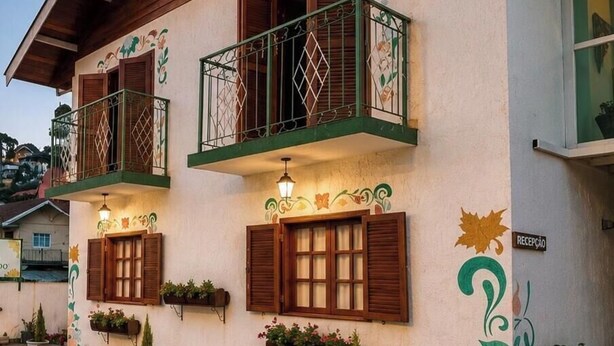Um edifício com varandas de madeira, área de estar ao ar livre e arte decorativa nas paredes.