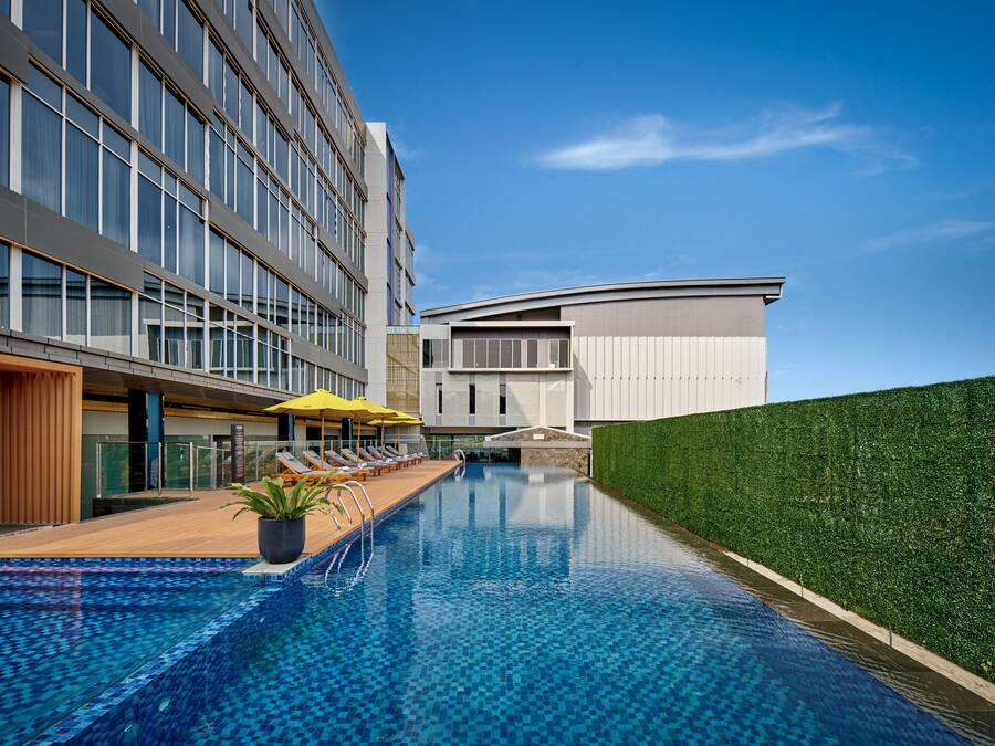 Um hotel moderno com piscina, espreguiçadeiras e um jardim bem cuidado.