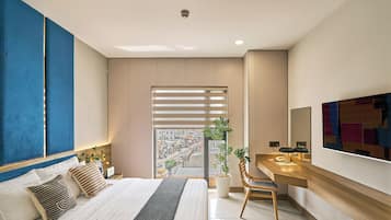 Quarto moderno com cama, mesa de cabeceira e vista da cidade pela janela.