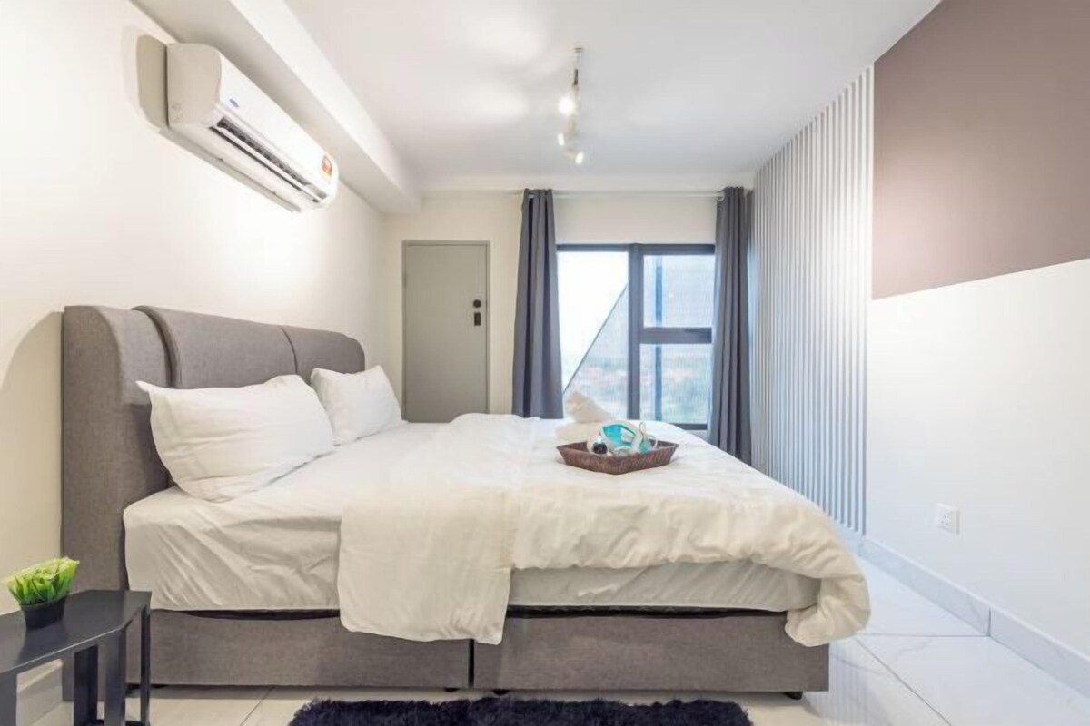 Um quarto moderno com uma cama grande, uma mesinha de cabeceira com uma planta e um aparelho de ar condicionado na parede.