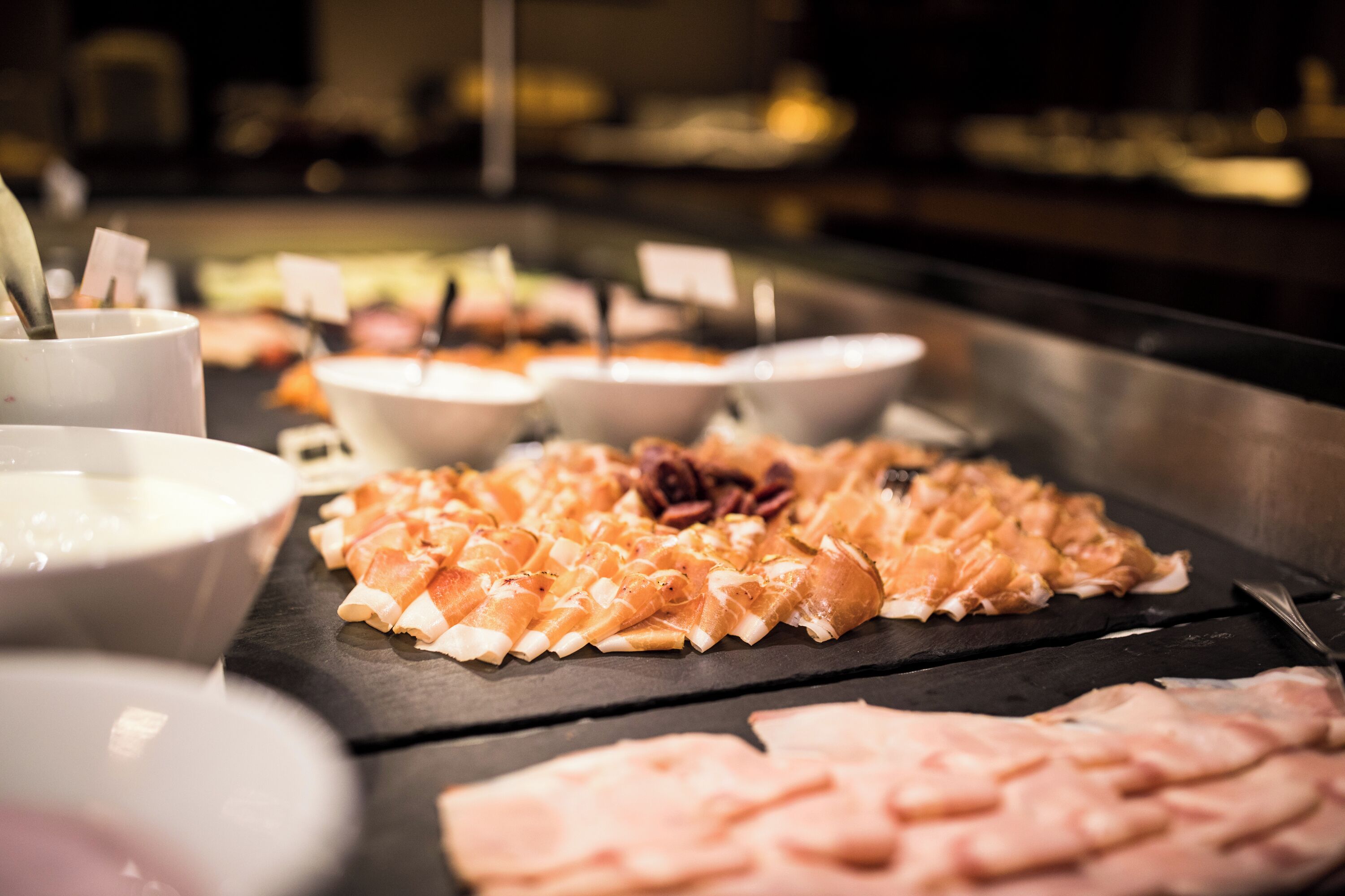 Buffet com diversos pratos, incluindo carnes fatiadas e uma variedade de alimentos dispostos ao centro.