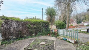 Um jardim com um canteiro elevado, uma palmeira e uma cerca.