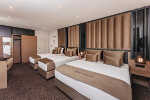 Quarto de hotel com duas camas, uma escrivaninha e um guarda-roupa.
