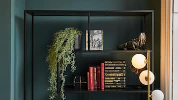 Uma estante com livros, uma fotografia, uma pequena estátua e uma planta.