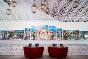 Uma área de recepção com parede estampada, várias obras de arte emolduradas e duas áreas de estar vermelhas.